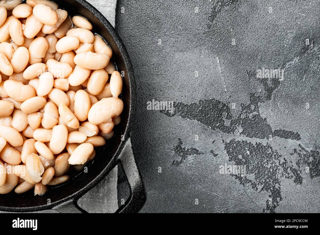 White kidney beans set, in cast iron frying pan, on gray stone ...