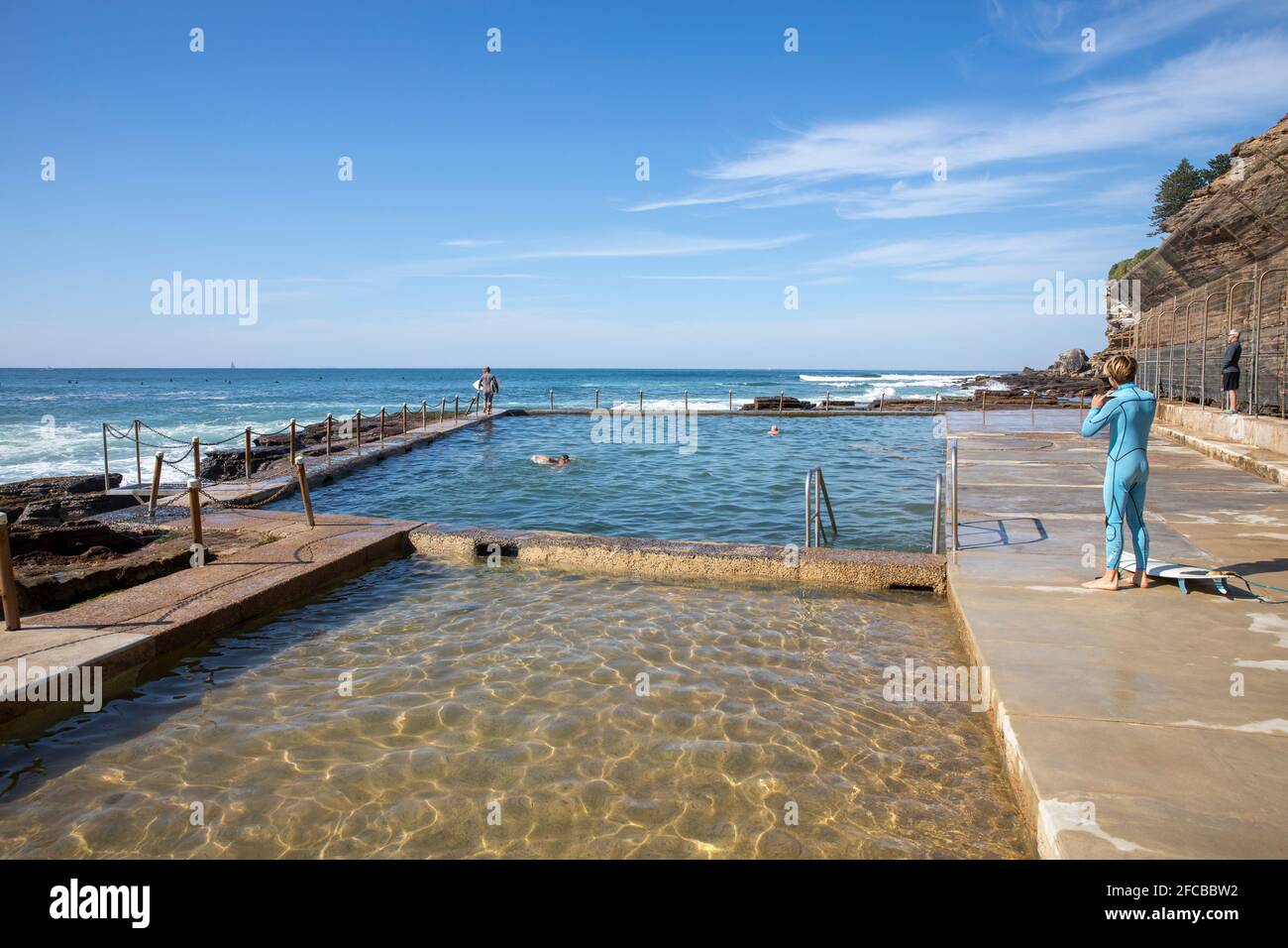 Young boy surfer stood at Avalon Beach ocean swimming pool on Sydney ...