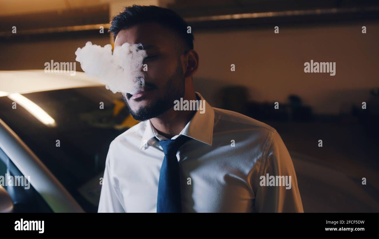 Adult mixed race relaxed man exhaling cloud of cigarette smoke. High ...