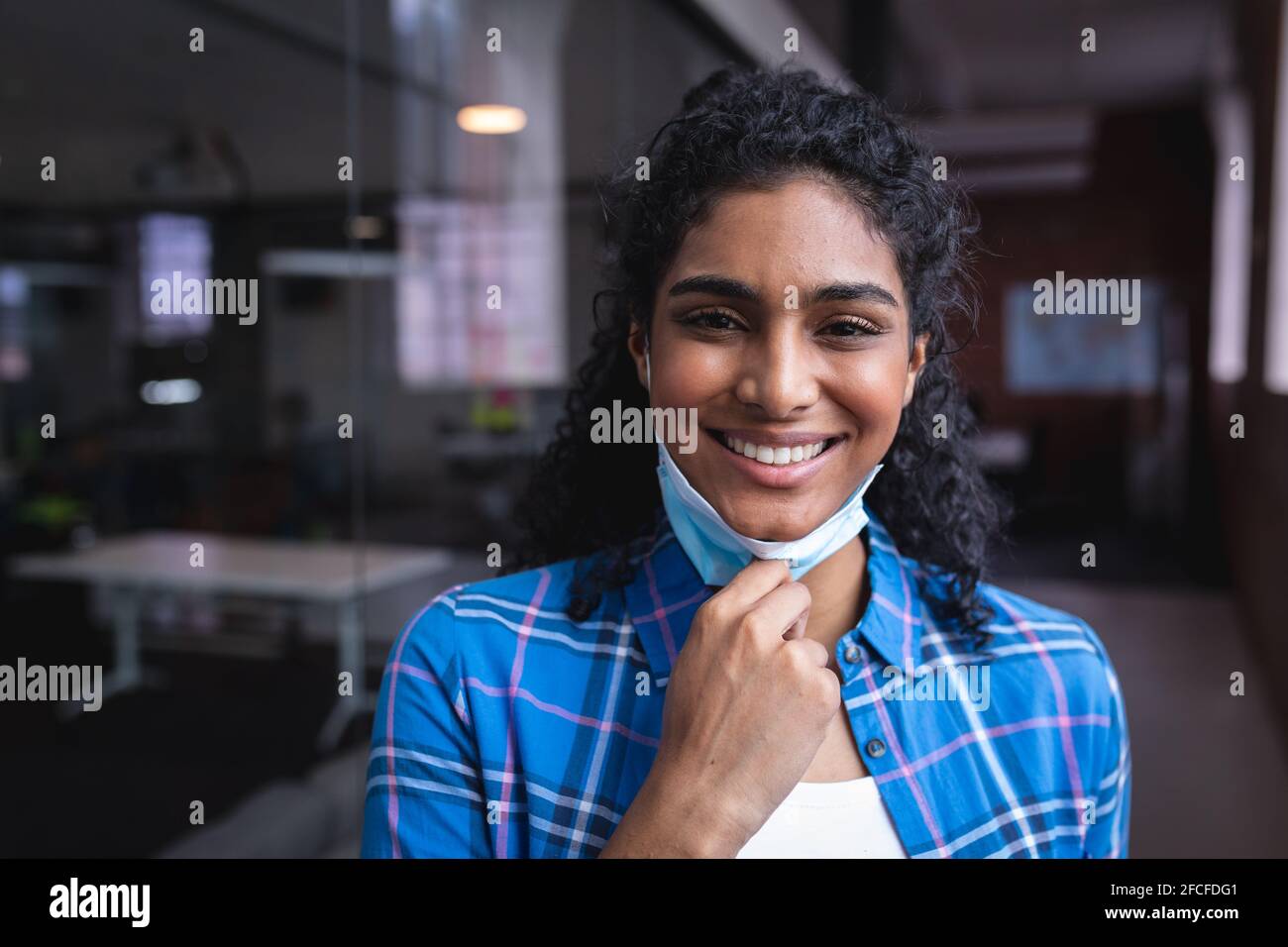 Portrait of happy mixed race businesswoman taking off face mask ...
