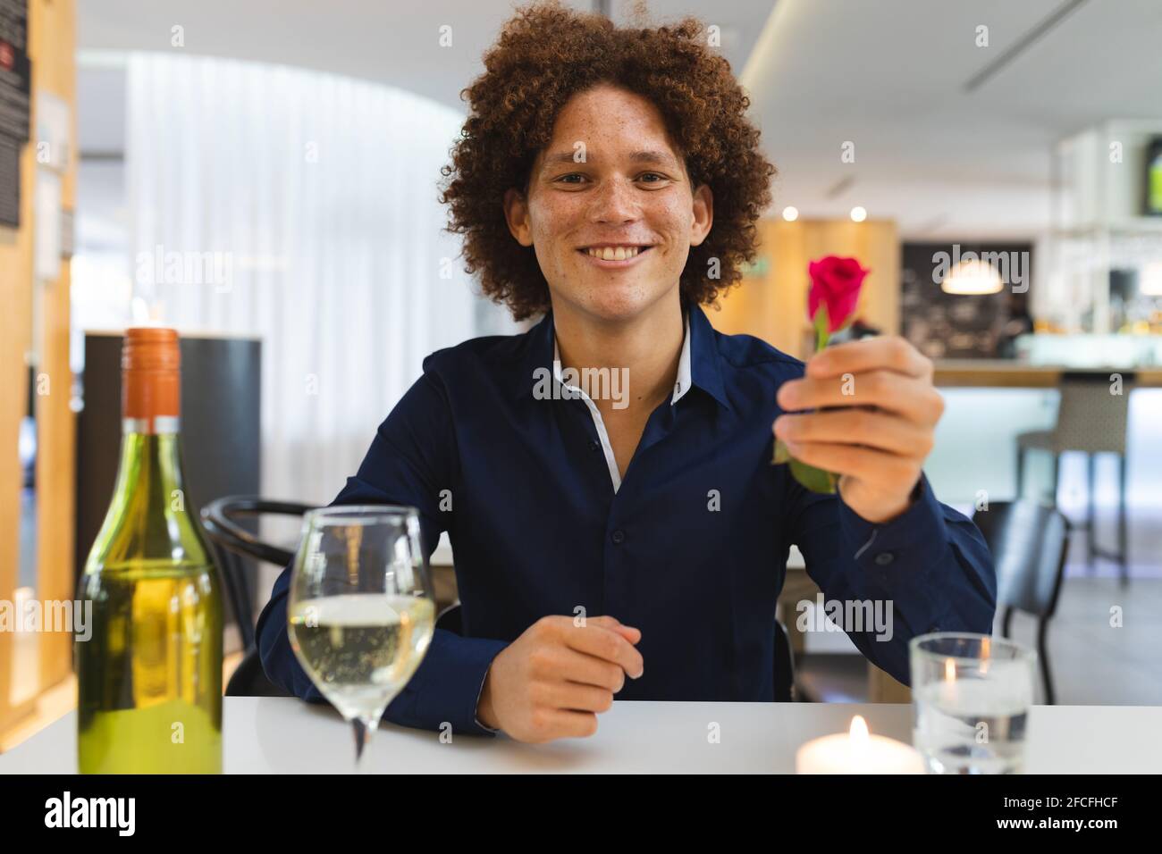 Mixed race man sitting at table in restaurant on dinner date holding ...