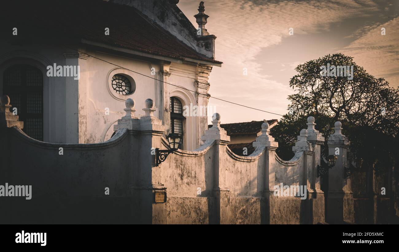 The old colonial church building and outside white walls with a street ...