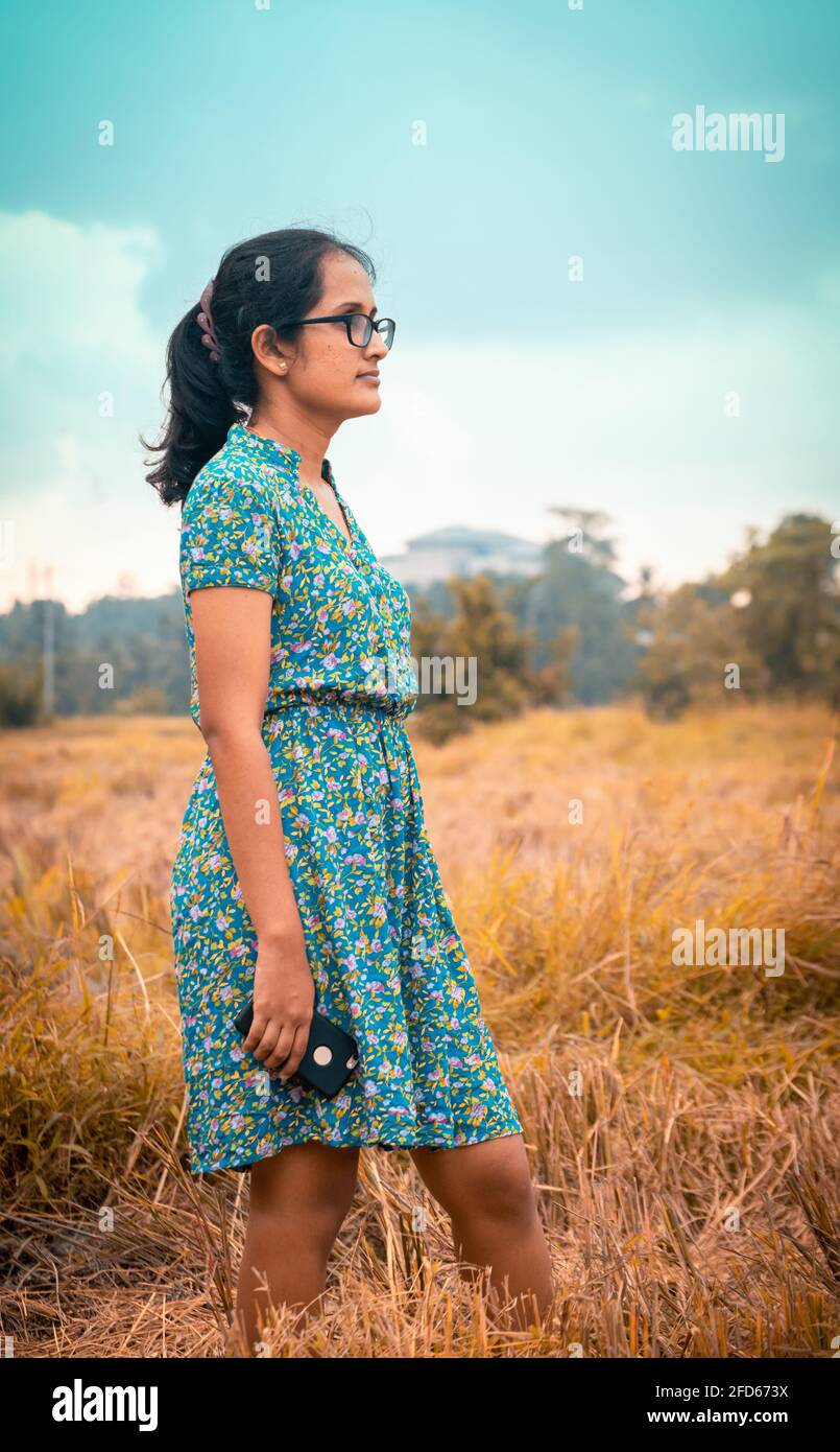 Beautiful Sri Lankan young girl in blue frock standing in a paddy field ...