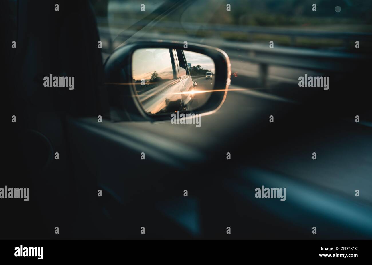 Car side mirror and the reflecting evening sunlight from the car body ...
