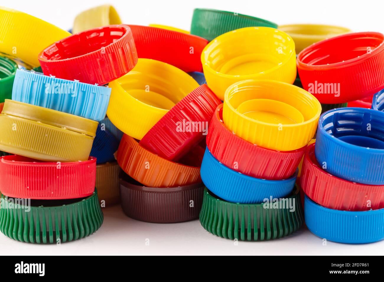 Many multi-colored plastic bottle caps on a white background. Recycling ...