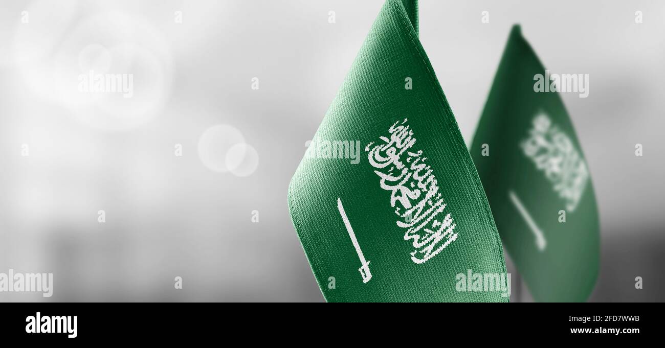 Small national flags of the Saudi Arabia on a light blurry background ...