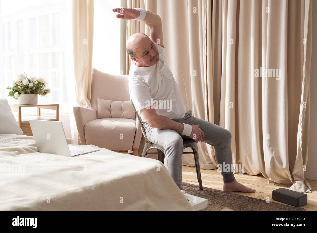 Senior caucasian man stretching side sitting on chair at his living ...
