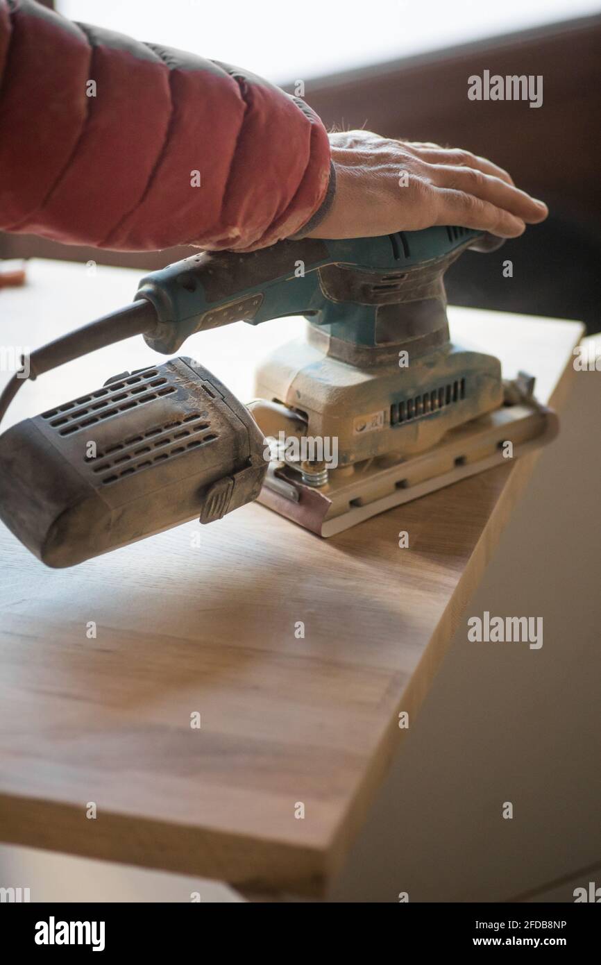 Man sanding wood plank using electric sand machine Stock Photo - Alamy