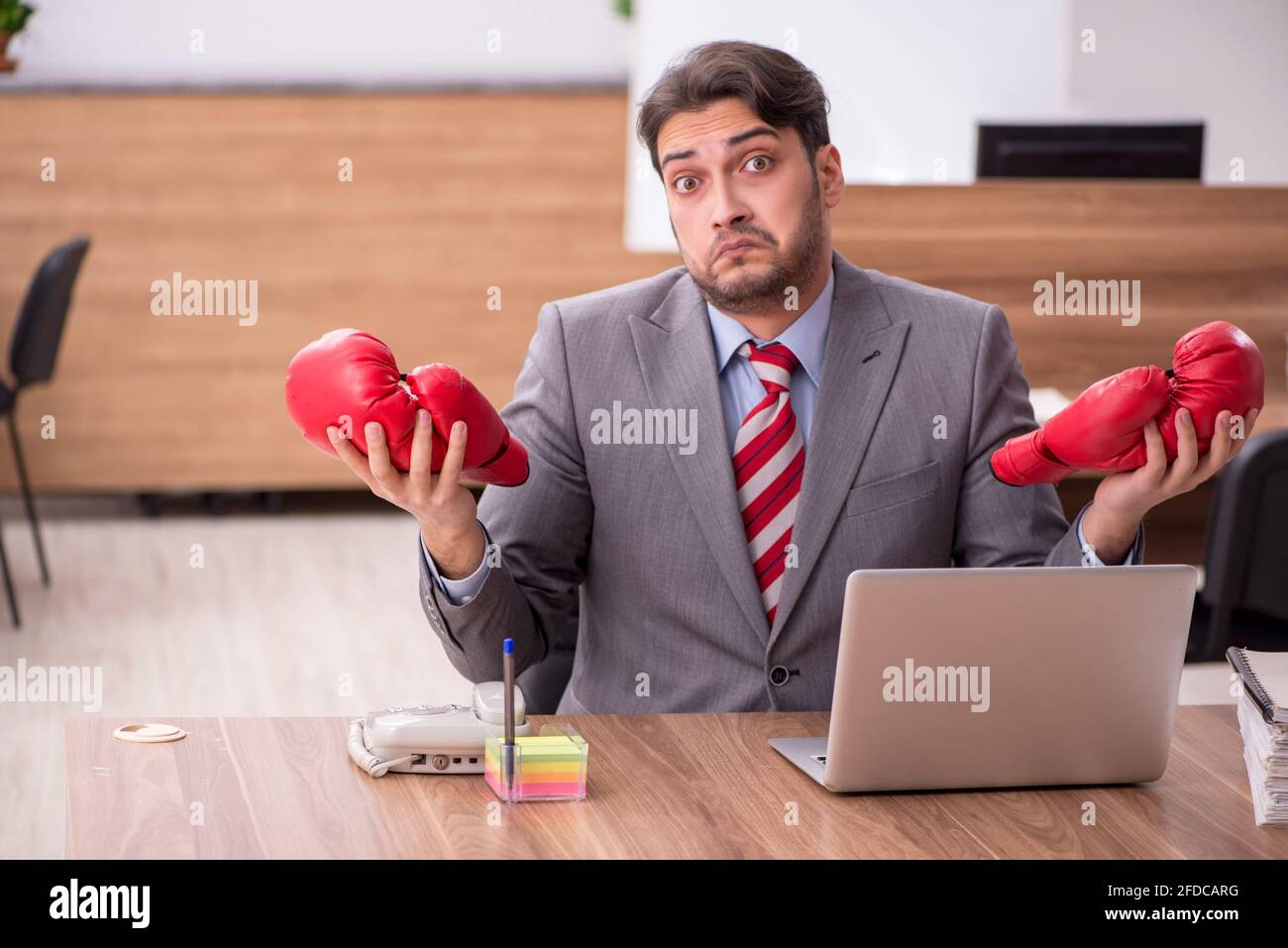 Young businessman employee wearing boxing gloves at workplace Stock ...