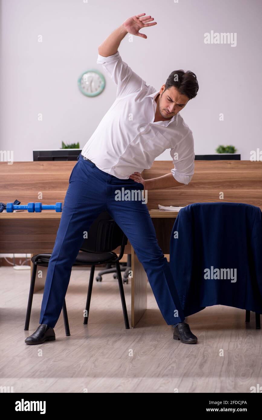 Young male employee doing sport exercises in the office Stock Photo - Alamy