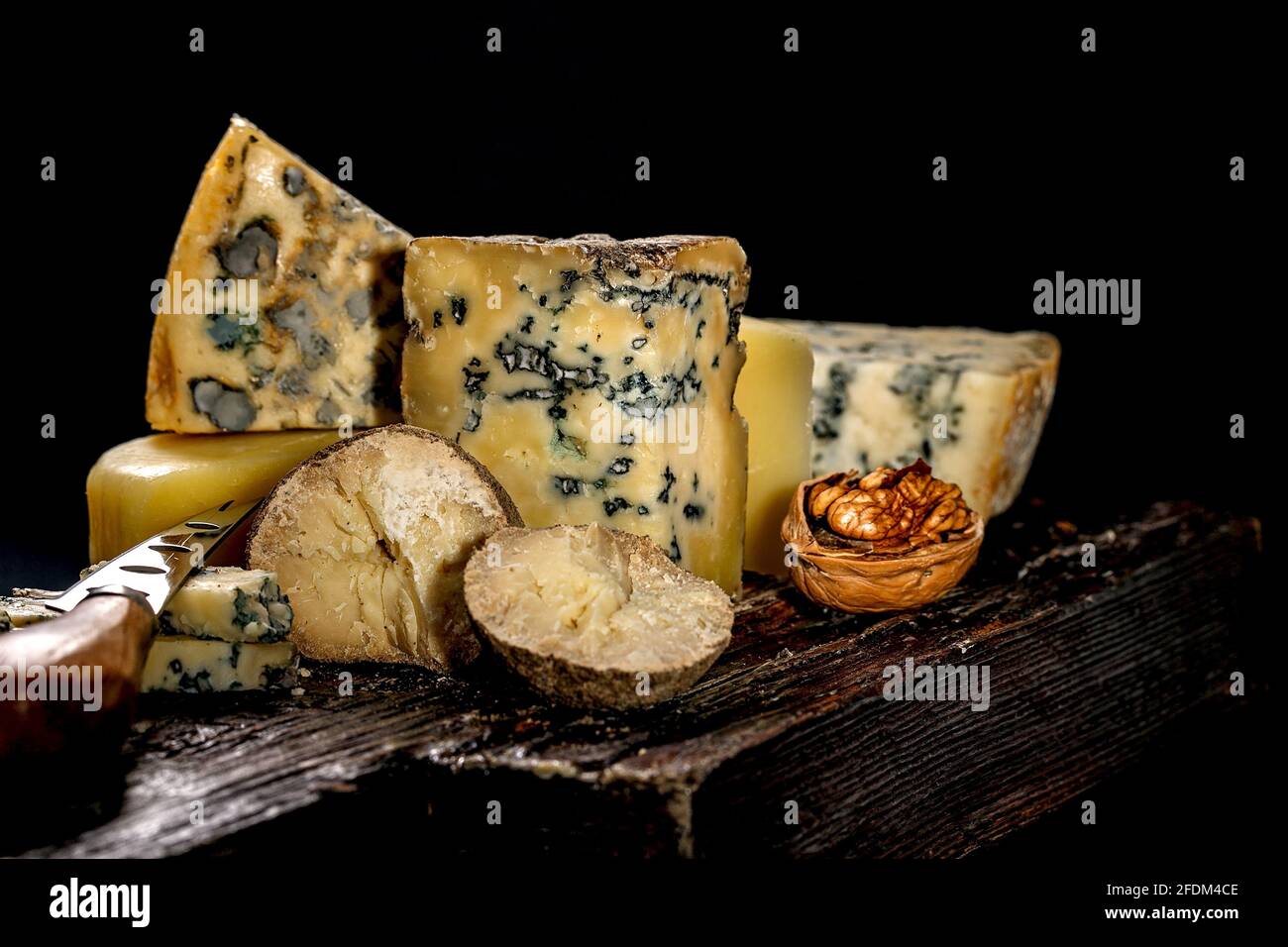 Assorted different luxury gourmet cheeses on a wooden board on a dark ...