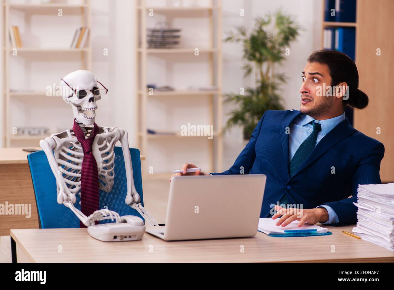 Dead employee working in the office in funny concept Stock Photo - Alamy