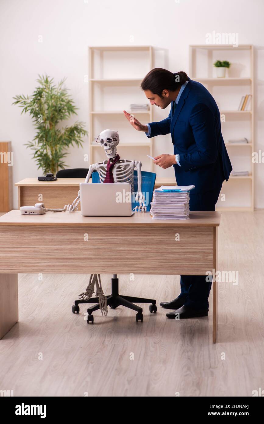 Dead employee working in the office in funny concept Stock Photo - Alamy