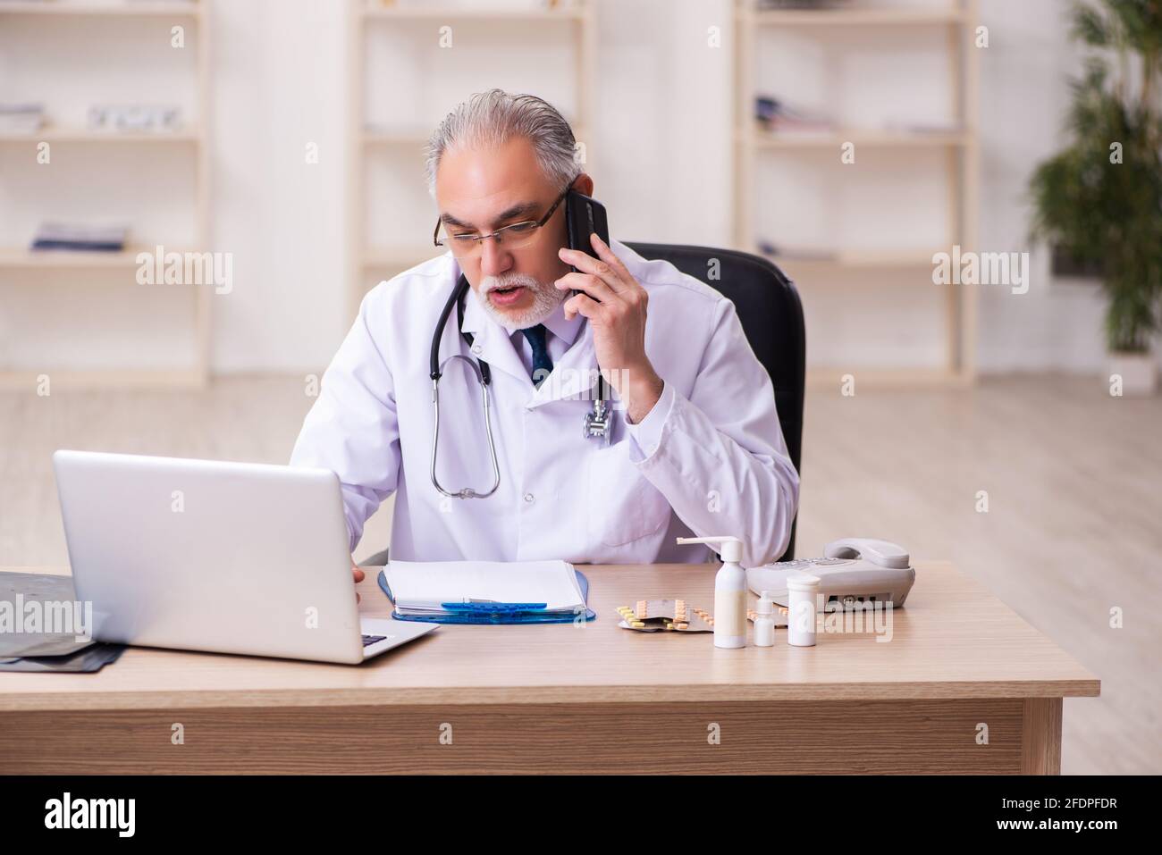 Old male doctor working in the clinic Stock Photo - Alamy