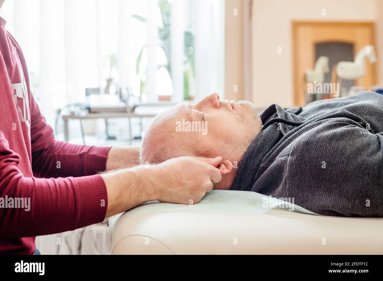 Male patient receiving cranial sacral therapy, lying on the massage ...