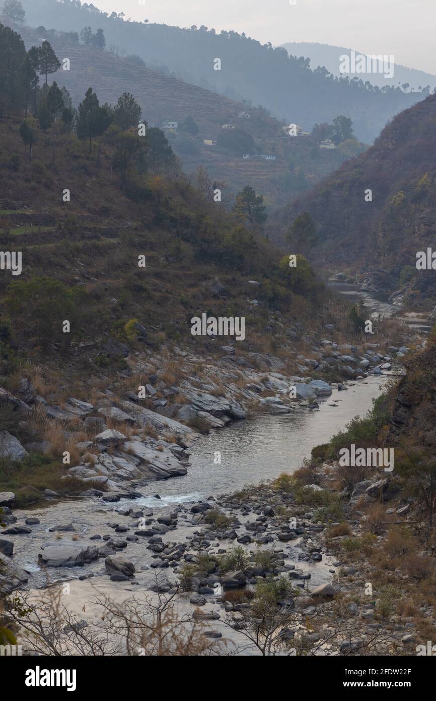 A river flowing through a narrow valley with stones and rocks scattered ...