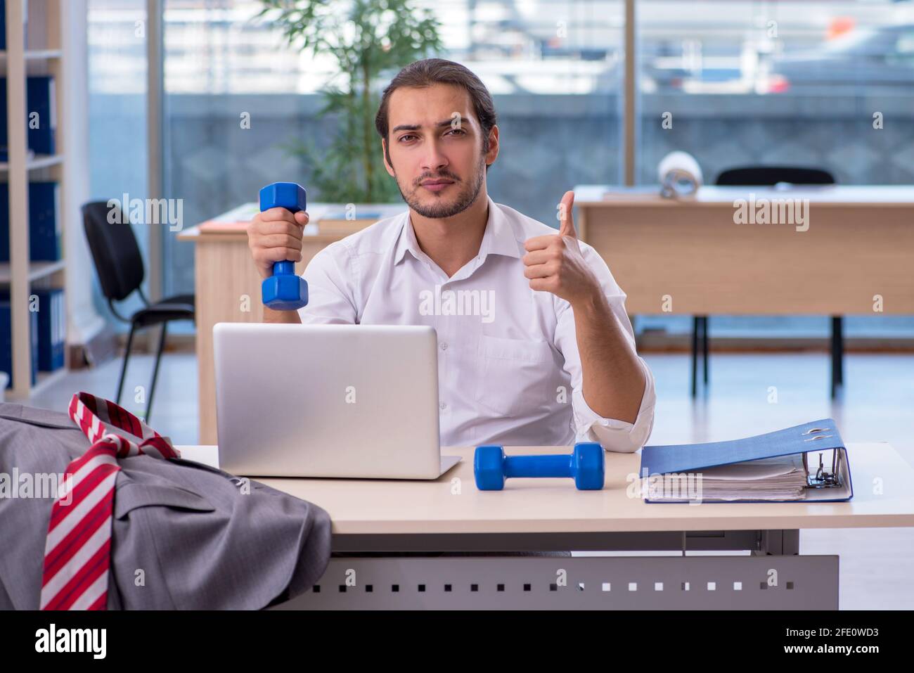 Young employee doing sport exercises at workplace Stock Photo - Alamy