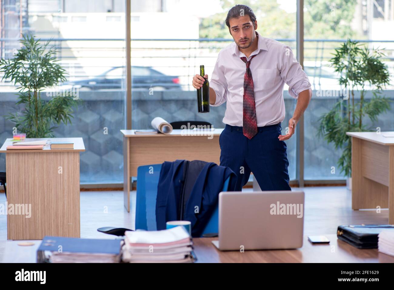 Young alcohol addicted employee working in the office Stock Photo - Alamy