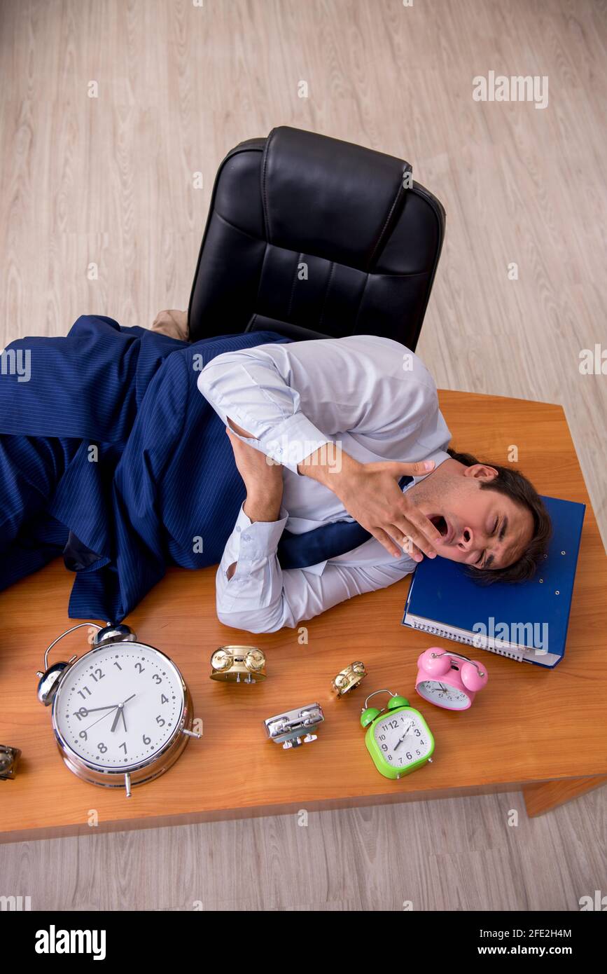 Young businessman sleeping in the office in time management concept ...