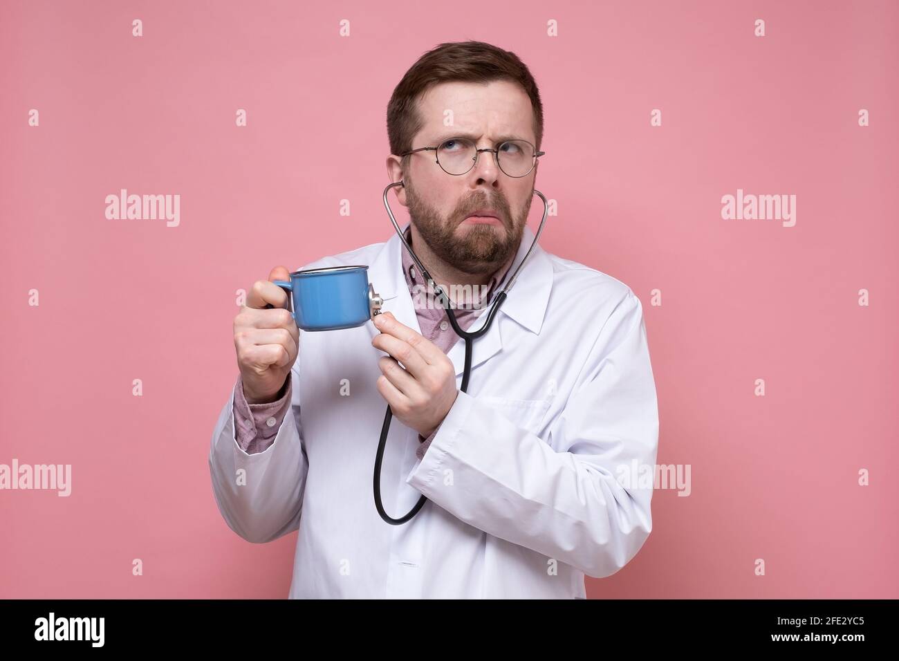 Perplexed, strange doctor with glasses holds a mug of coffee in hands ...