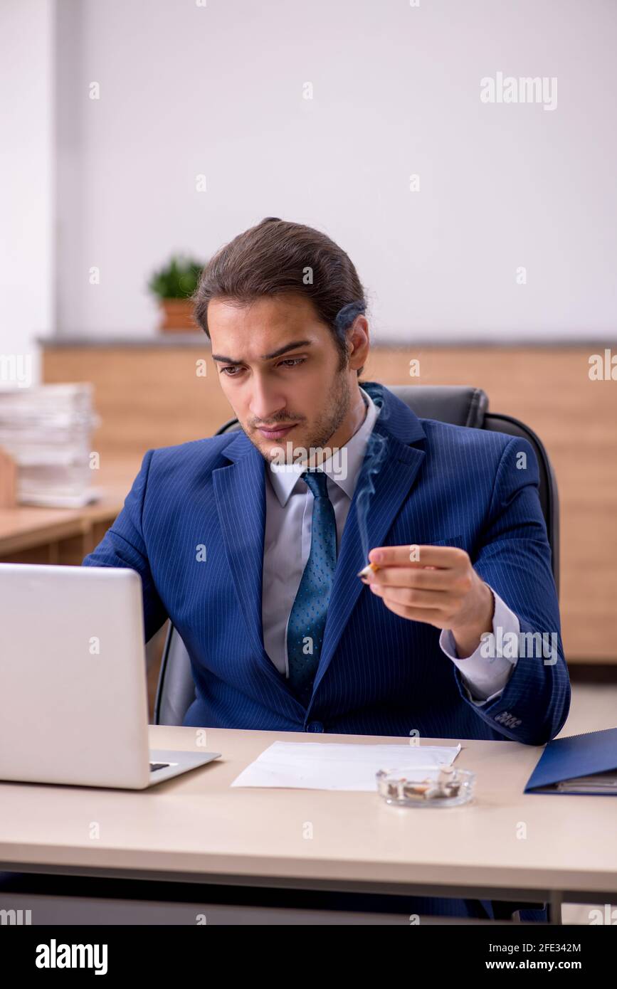 Young man employee smoking cigarettes in the office Stock Photo - Alamy