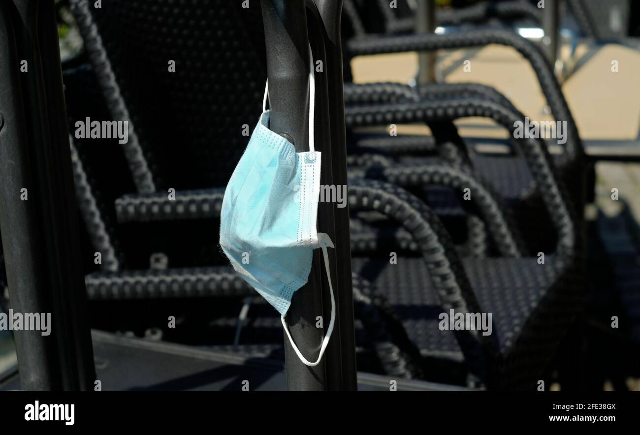 Face mask hanging on stacked chairs in a closed restaurant, food and ...