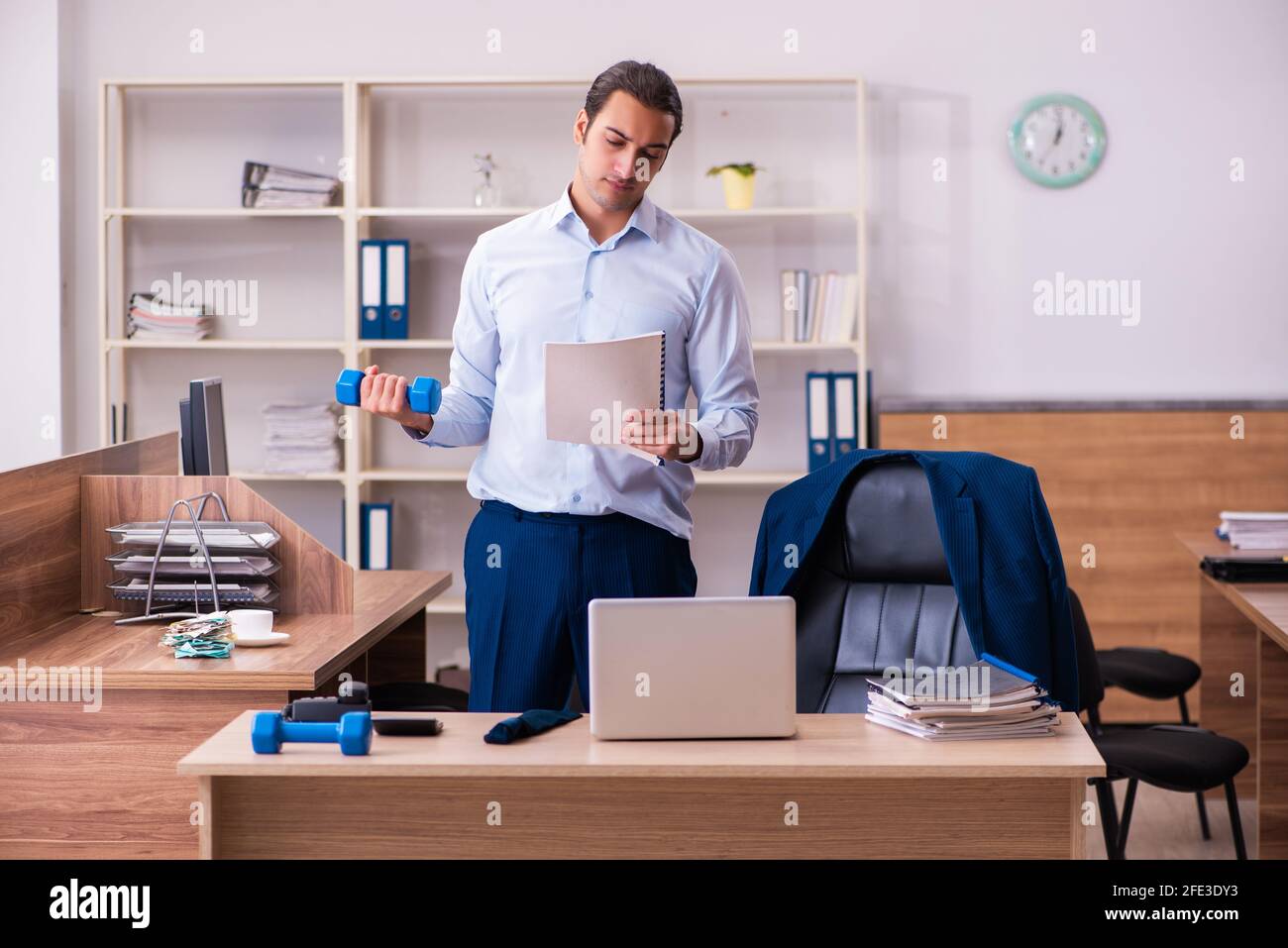 Young employee doing physical exercises at workplace Stock Photo - Alamy
