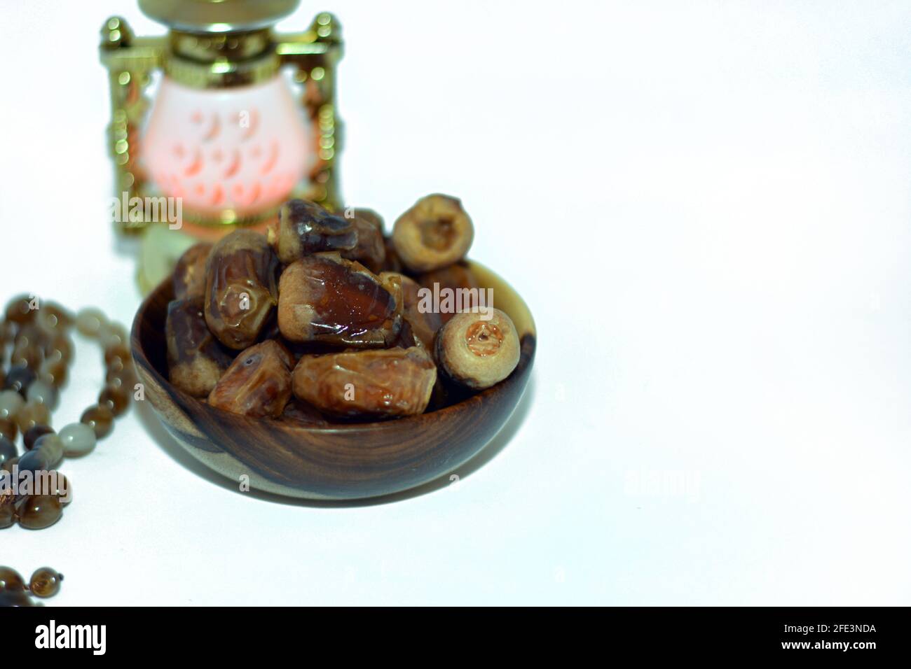 Dried dates fruit in a wooden bowl isolated on a white background with ...