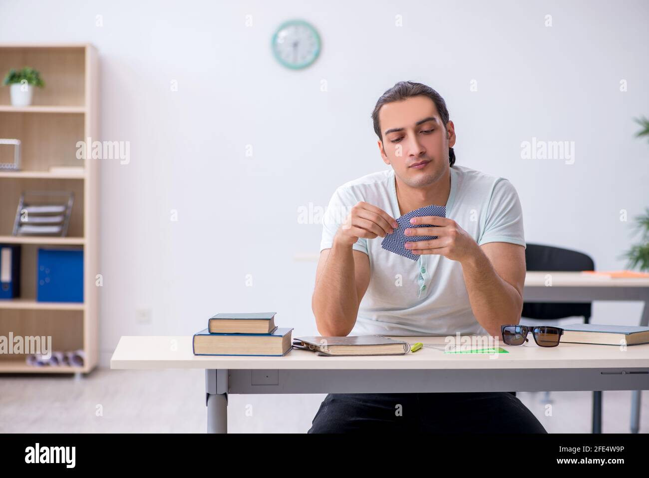 Male student playing cards during exam preparation in the classroom ...