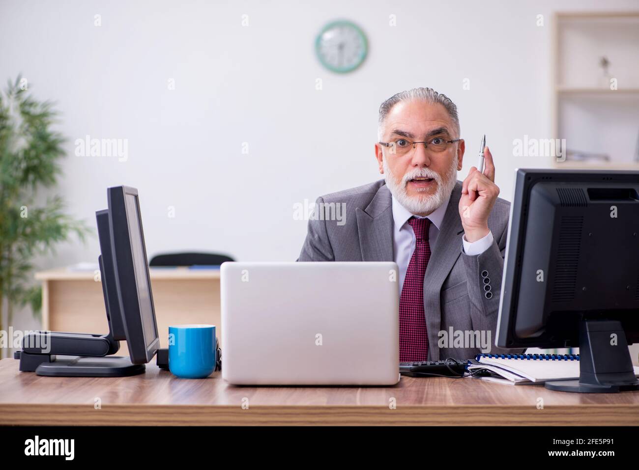 Old boss sitting at desktop in the office Stock Photo - Alamy