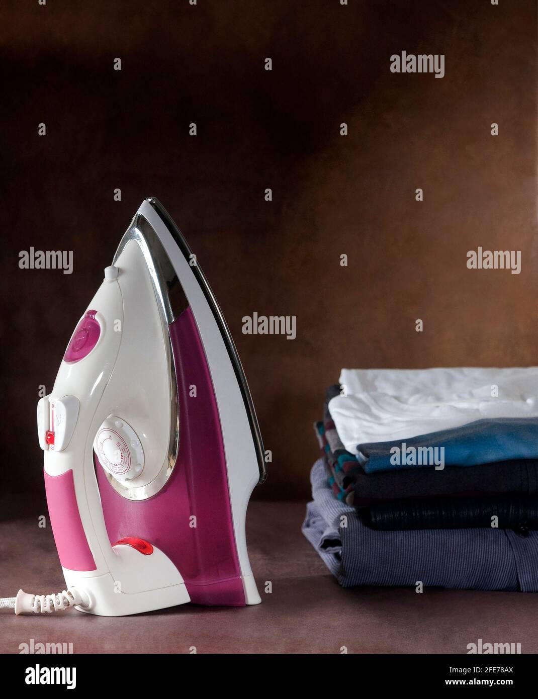 A modern iron for ironing linen, clothes, fabrics. A stack of ironed ...