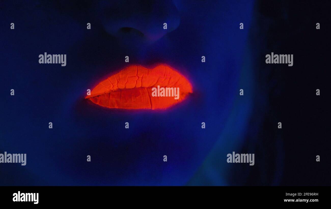Young girl with red lips showing tongue in ultraviolet light Stock ...