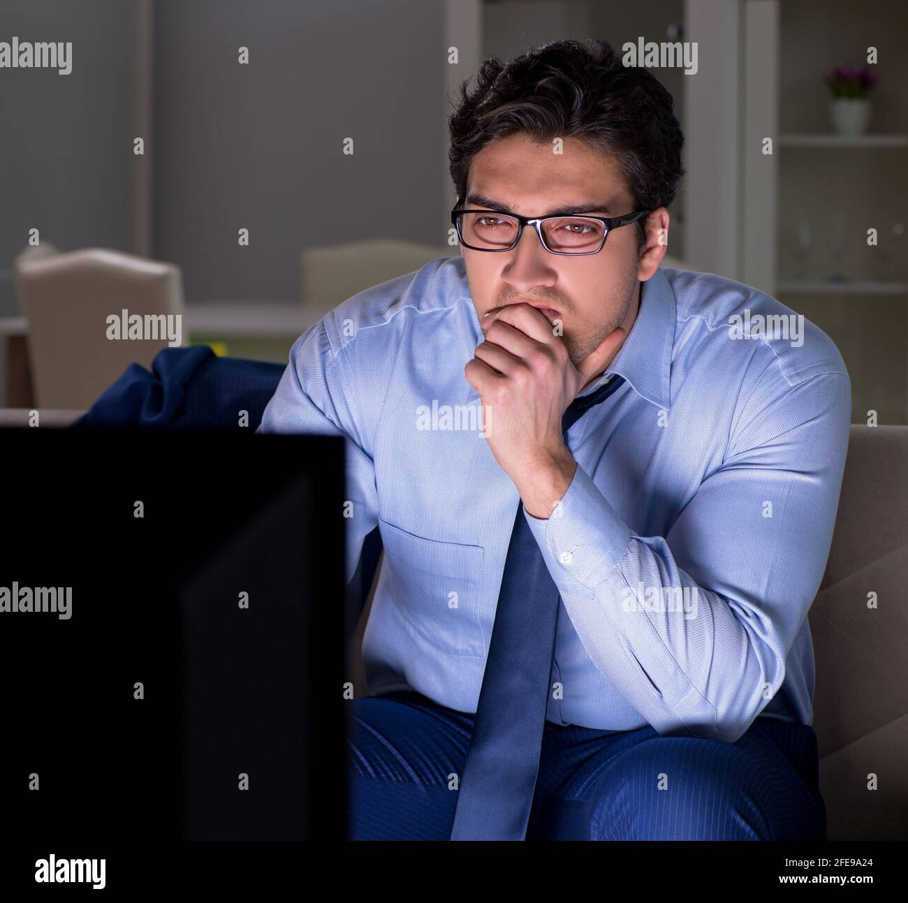 The businessman watching tv at night late Stock Photo - Alamy