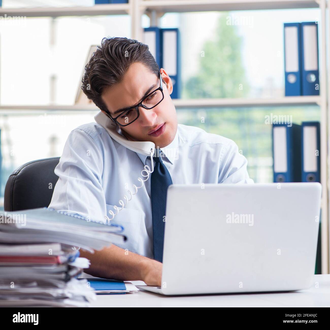 The businessman with excessive work paperwork working in office Stock ...