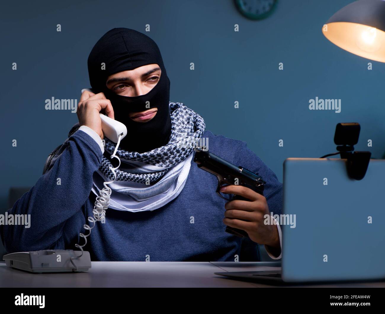 The terrorist burglar with gun working at computer Stock Photo - Alamy