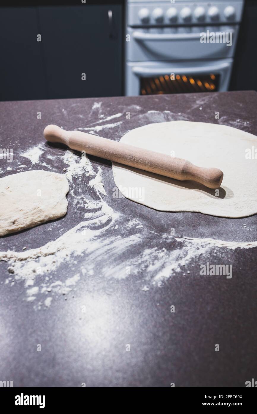 pizza dough being rolled on kitchen benchtop with oven in the ...