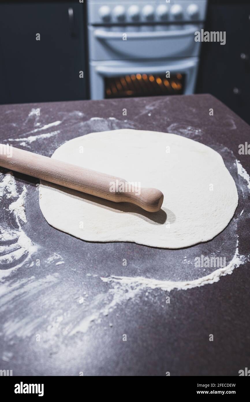pizza dough being rolled on kitchen benchtop with oven in the ...