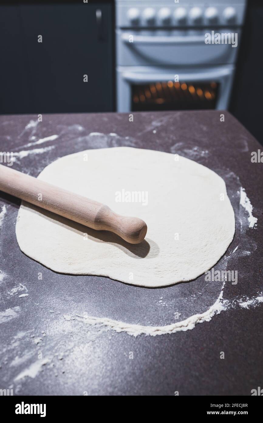 pizza dough being rolled on kitchen benchtop with oven in the ...