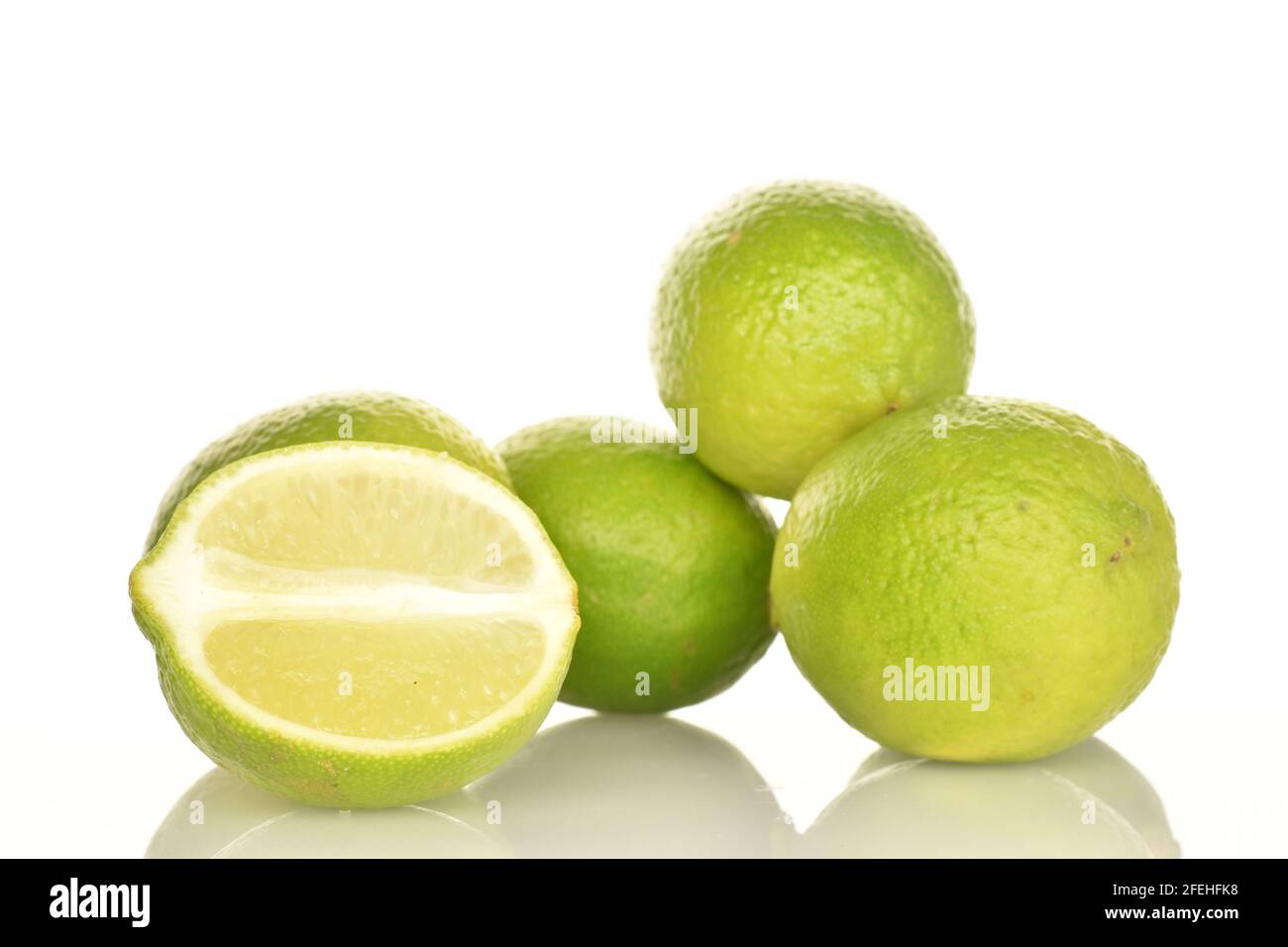 Several whole and one half juicy limes, close-up, on a white background ...