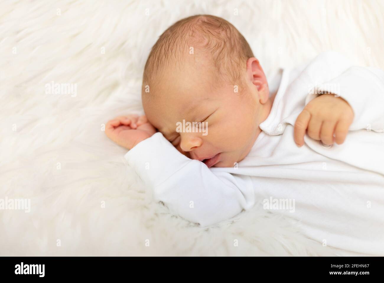 Adorable newborn one week age in white bedroom. Newborn child relaxing ...