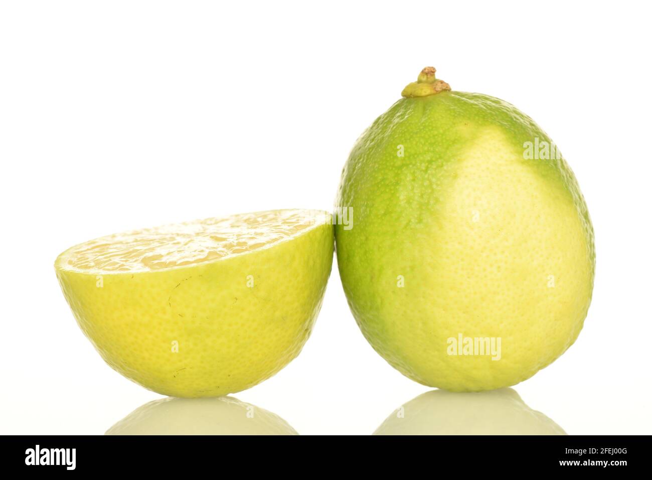 One whole and one half of a juicy lime, close-up, against a white ...