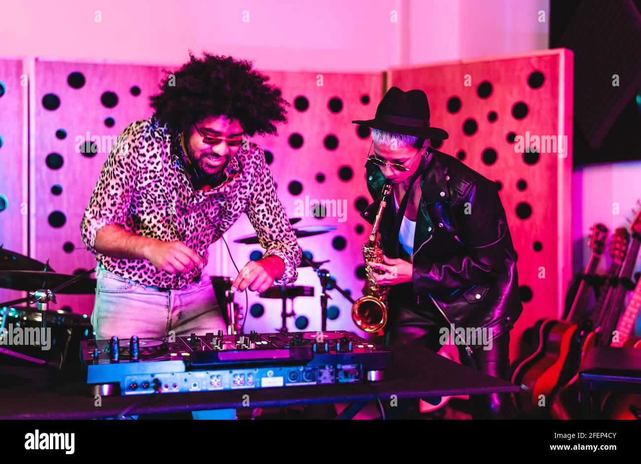 Young happy people playing music with dj mixer and saxophone in house ...