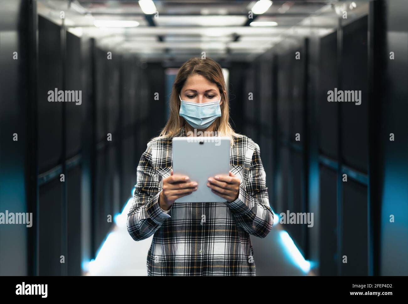Female informatic engineer working inside server room database while ...