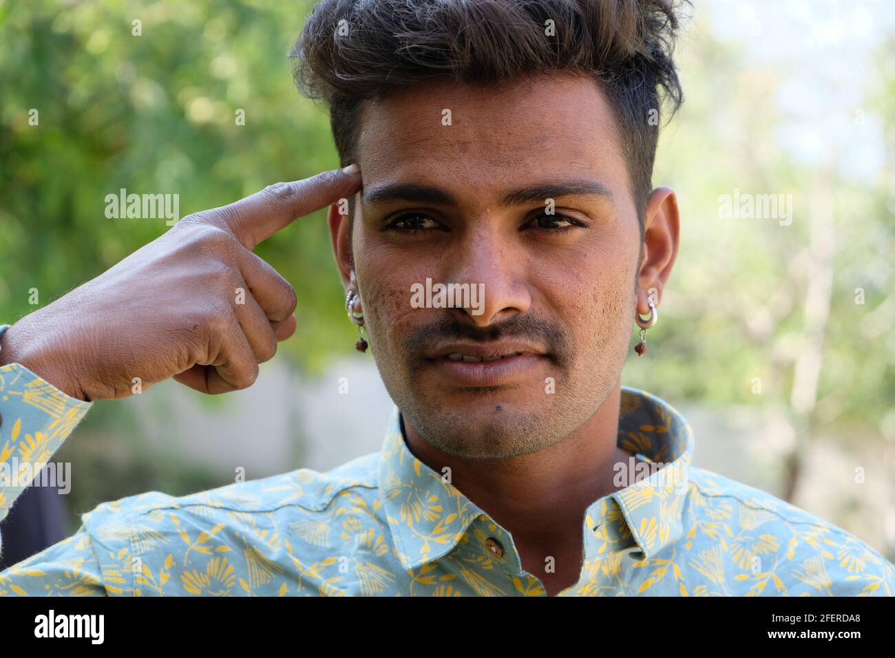 Portrait of an Indian young male pointing on his head and looking aside ...
