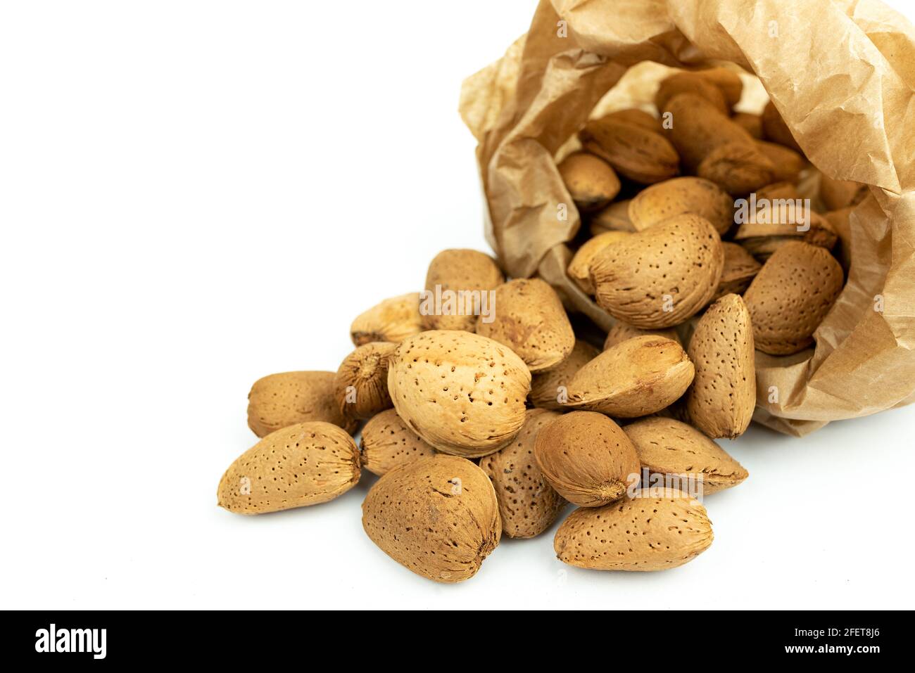 bunch of shelled almonds going out of a recycled kraft paper bag with a ...