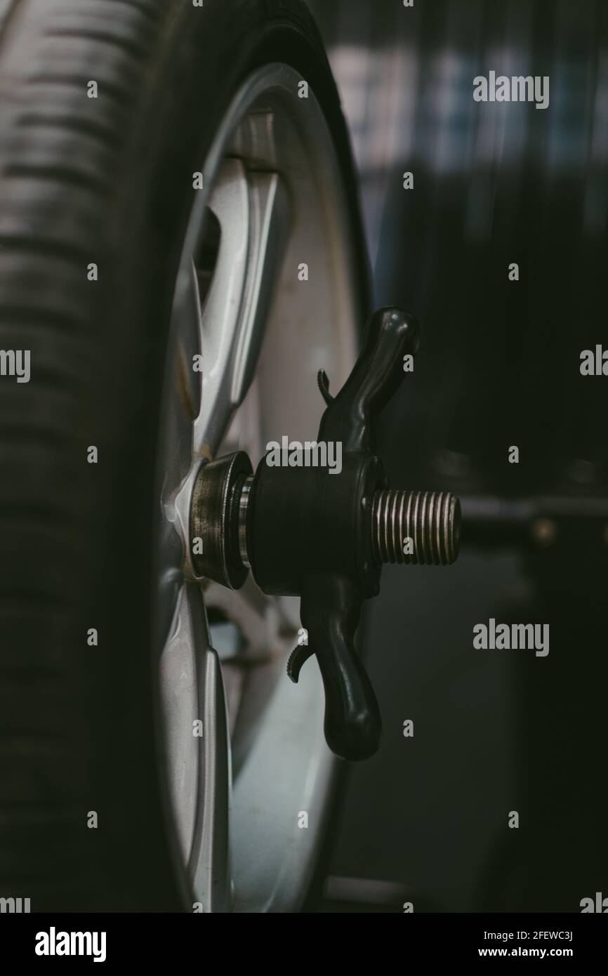 Vertical shot of a car wheel in a workshop with a tool removing the rim ...