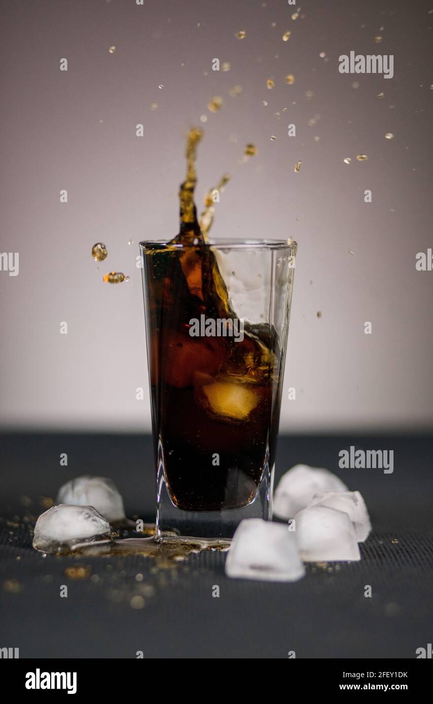 ice falls into a glass with a drink and splashes around Stock Photo - Alamy
