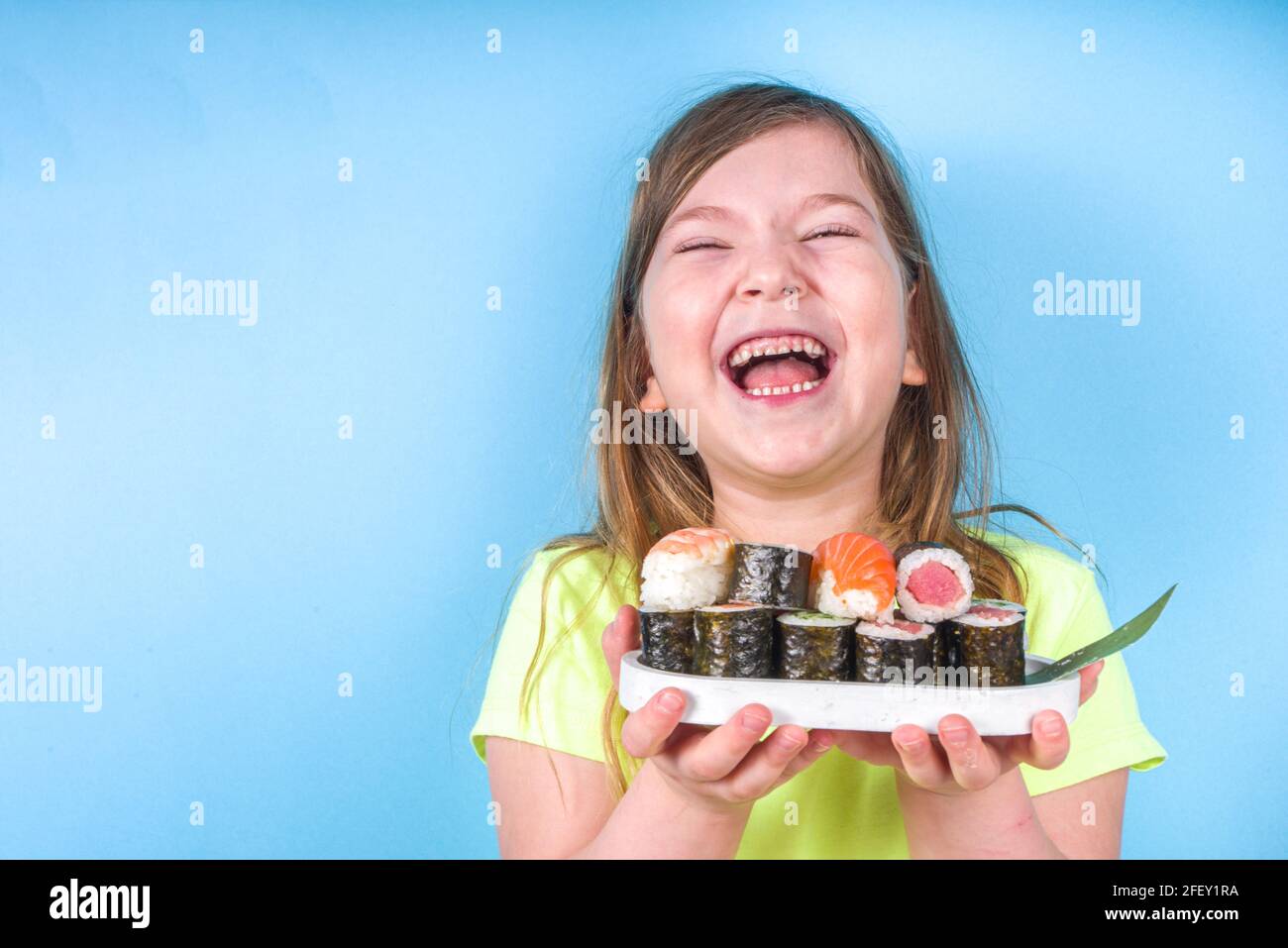 Cute little girl enjoys eating sushi. Cheerful funny caucasian blond ...