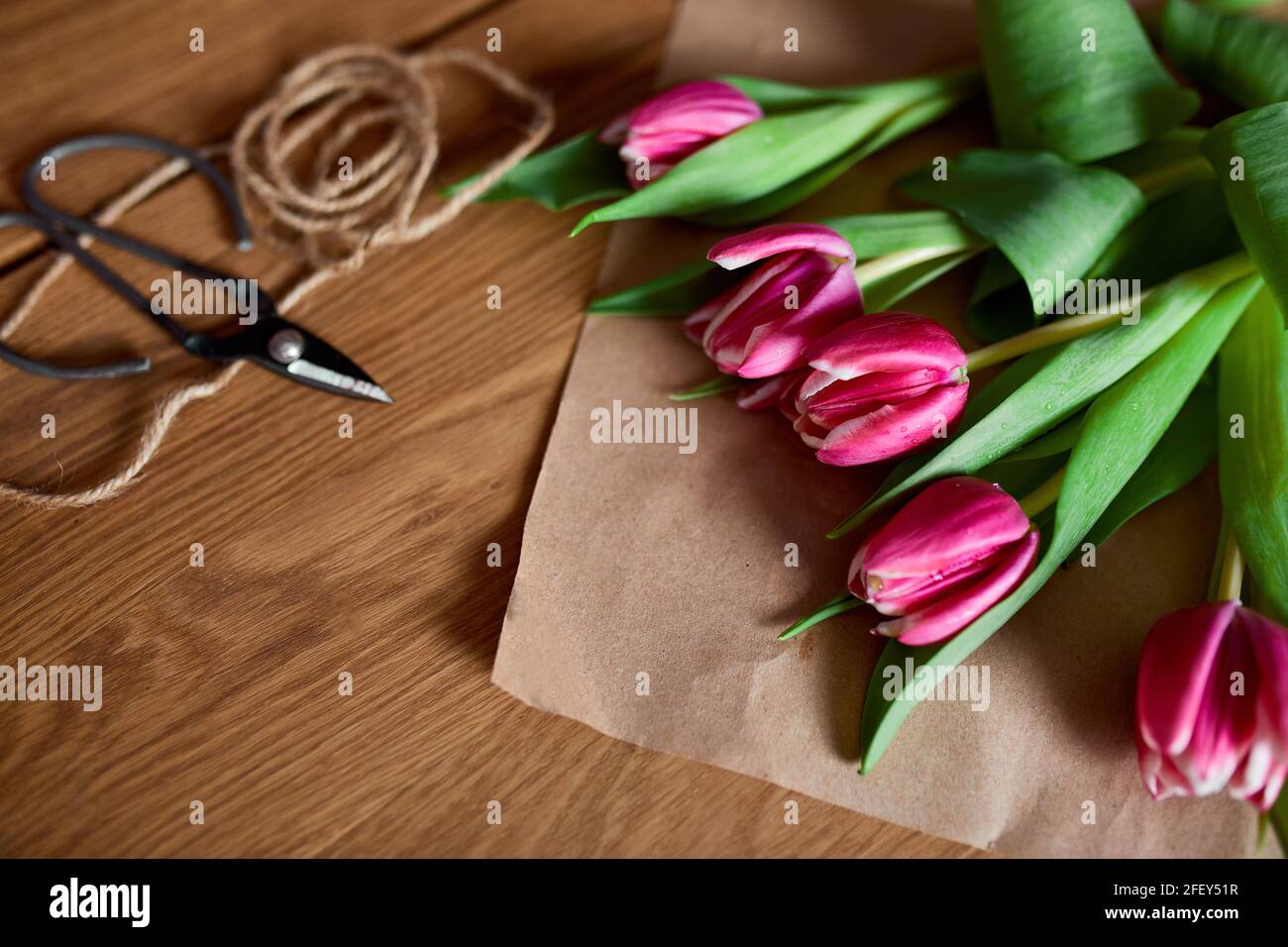 Floristic workplace with craft paper, twine Arranging pink tulips ...