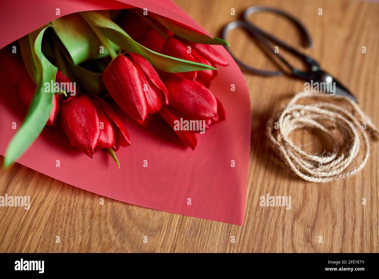Floristic workplace with craft paper, twine Arranging red tulips ...